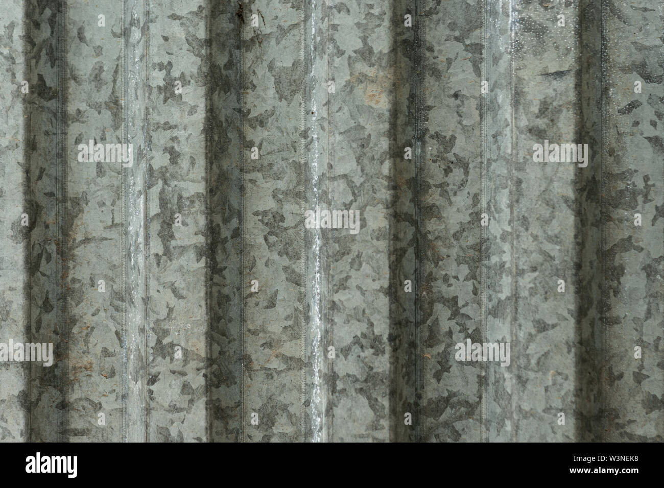 The corrugated metal surface of grey color with runs of old paint ...