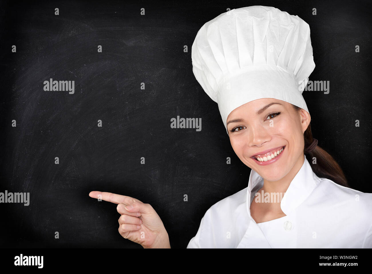 Chef pointing showing blank menu blackboard. Happy female chef, cook or ...