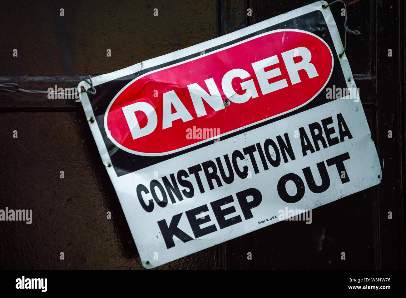 Crooked old metal warning sign that reads DANGER CONSTRUCTION AREA KEEP ...