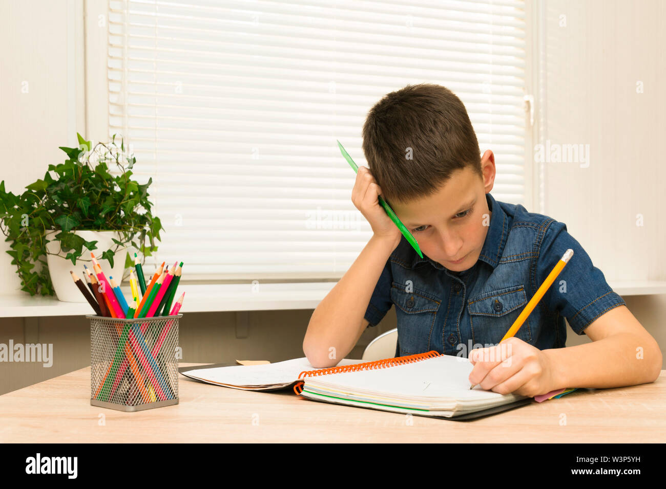 young kid, boy doing homework at home, writing in notebook Stock Photo ...