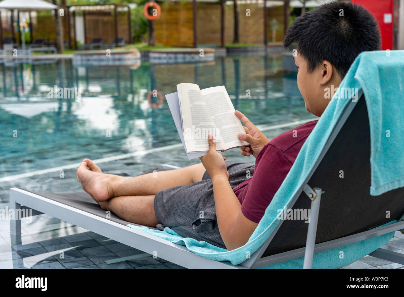 Man relaxing and reading book at swimming pool Stock Photo - Alamy