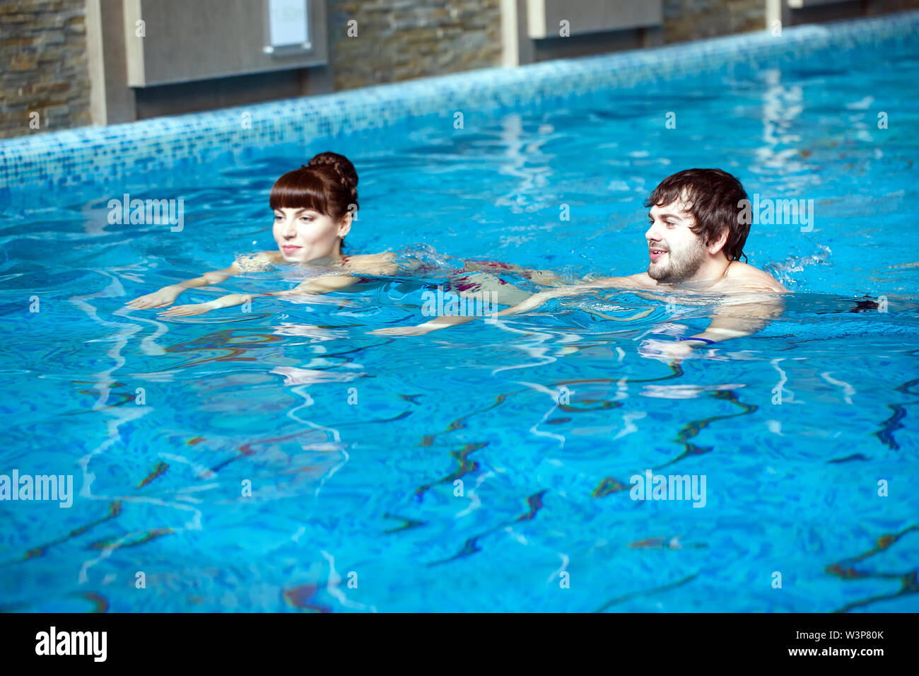 Couple swimming in the pool. Lovers spend time together in the pool ...