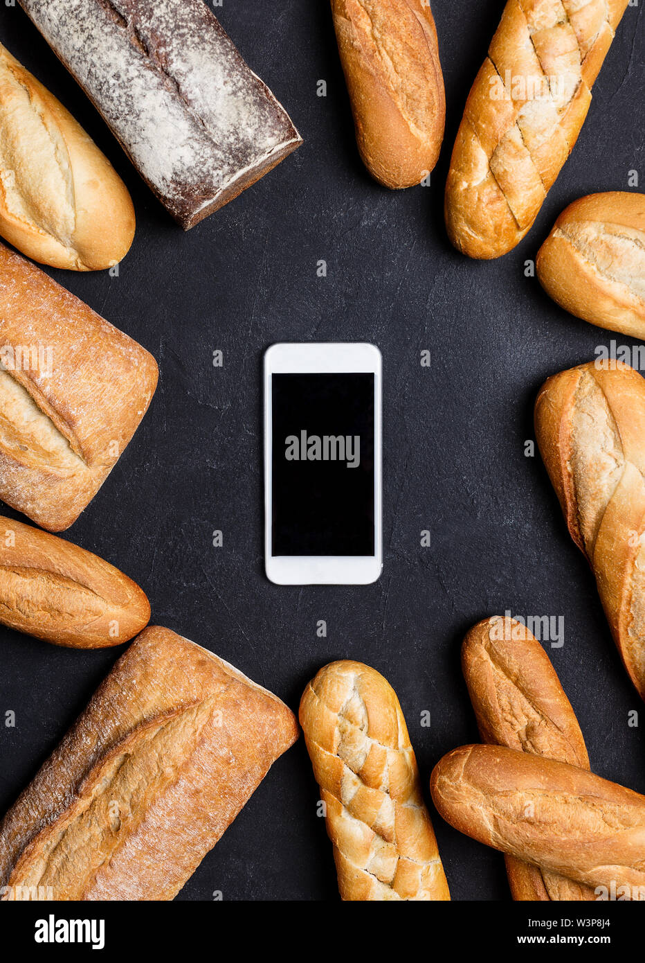 Copy space with bread and cellphone on black background. Flat lay items ...