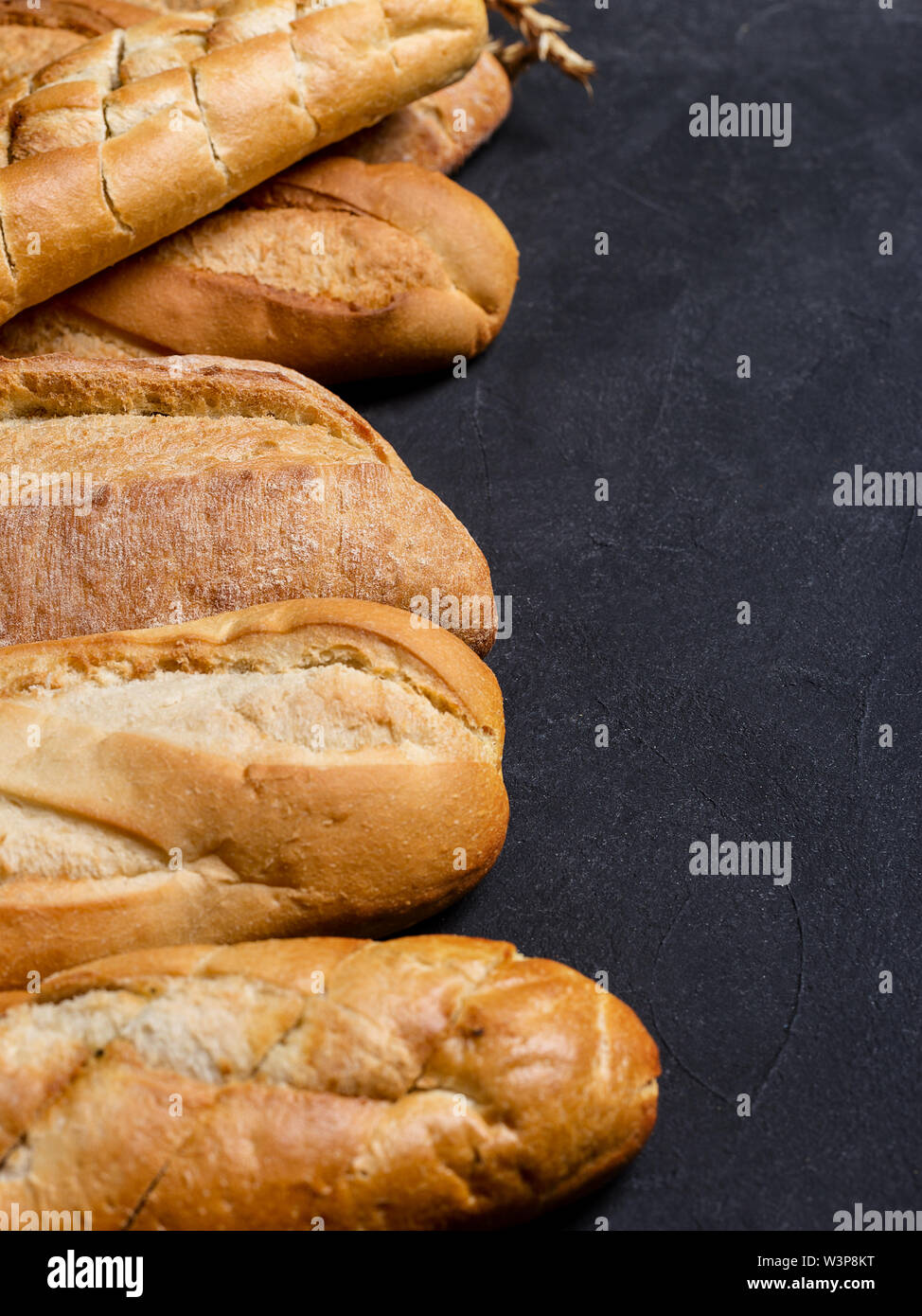 Various of tasty fresh bread on black background. Left edge copy space ...