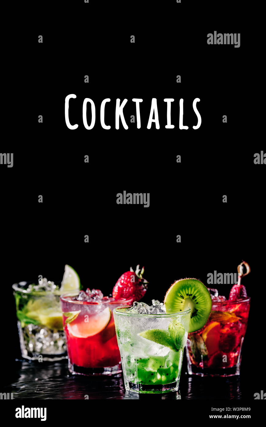Four colorful tasty alcoholic cocktails in a row at the bar stand ...