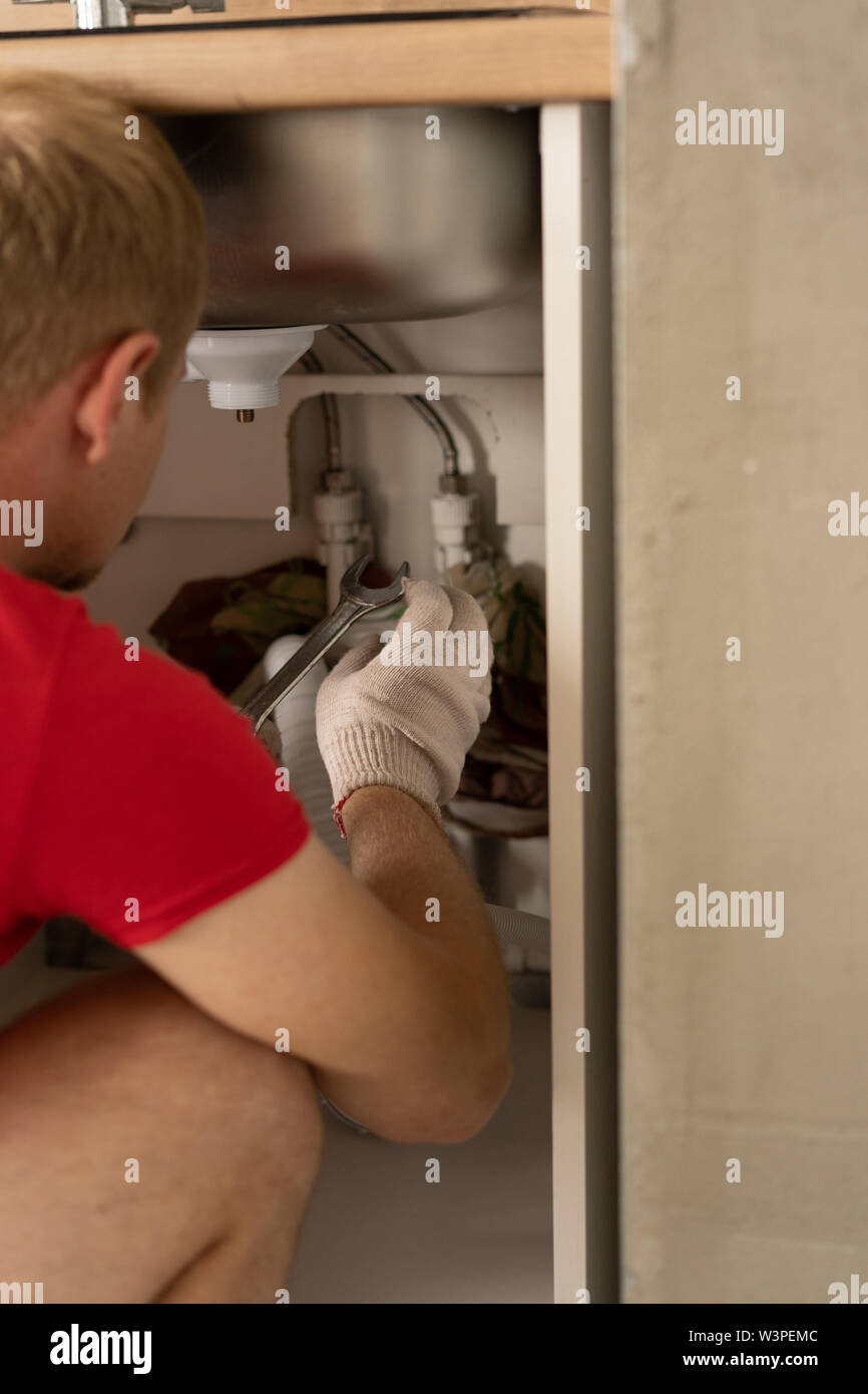 repair and decoration. plumber repairing water pipes in the kitchen ...
