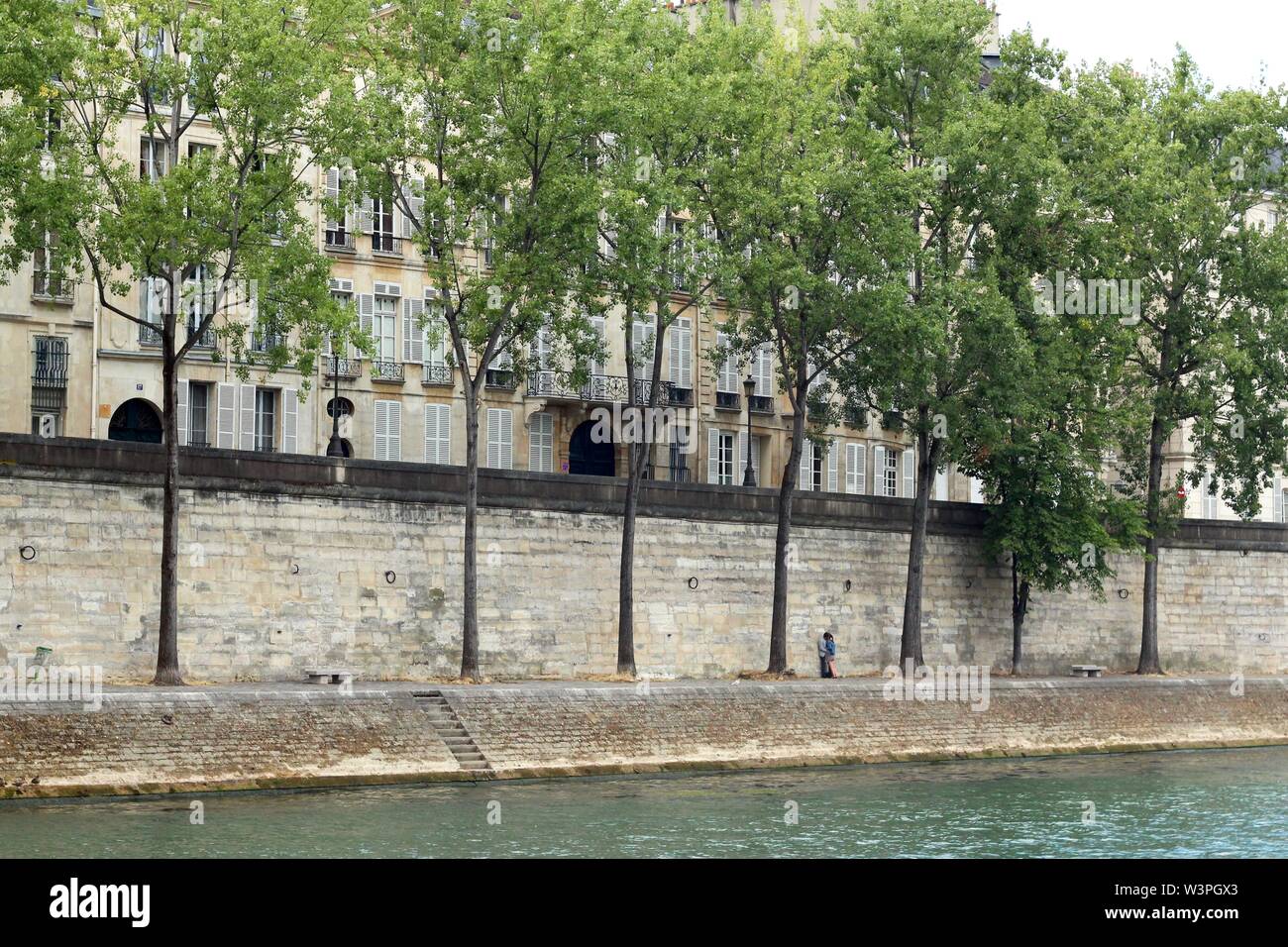 Wide shot of a beautiful canal and a stone fence with trees with a ...