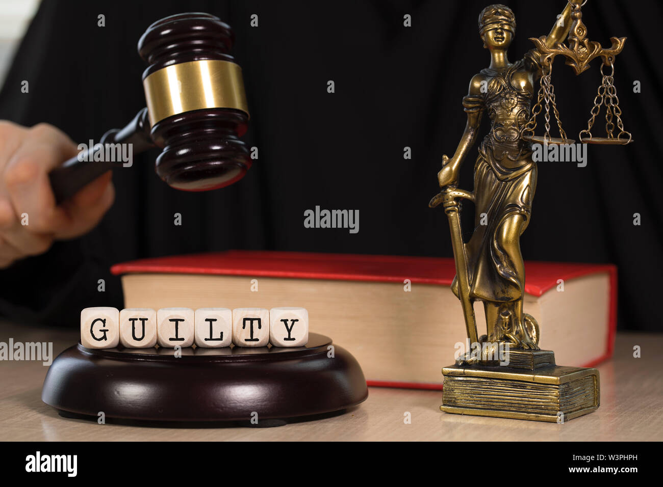 Word GUILTY composed of wooden dices. Wooden gavel and statue of Themis ...