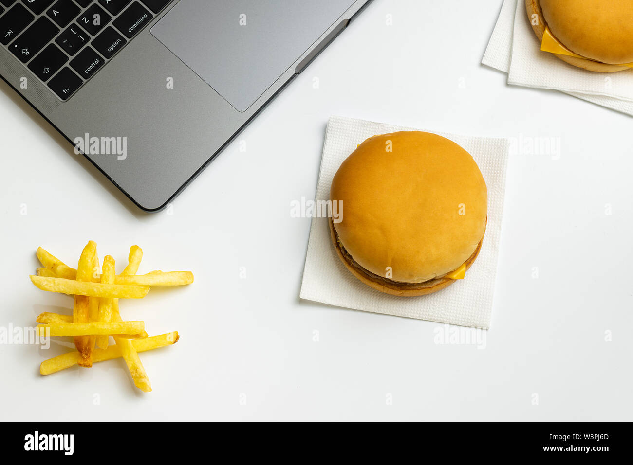 Fast food at work snacking. Laptop, hamburger and french fry at ...
