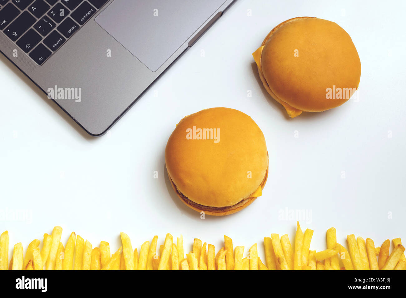 Fast food at work snacking. Laptop, hamburger and french fry at ...