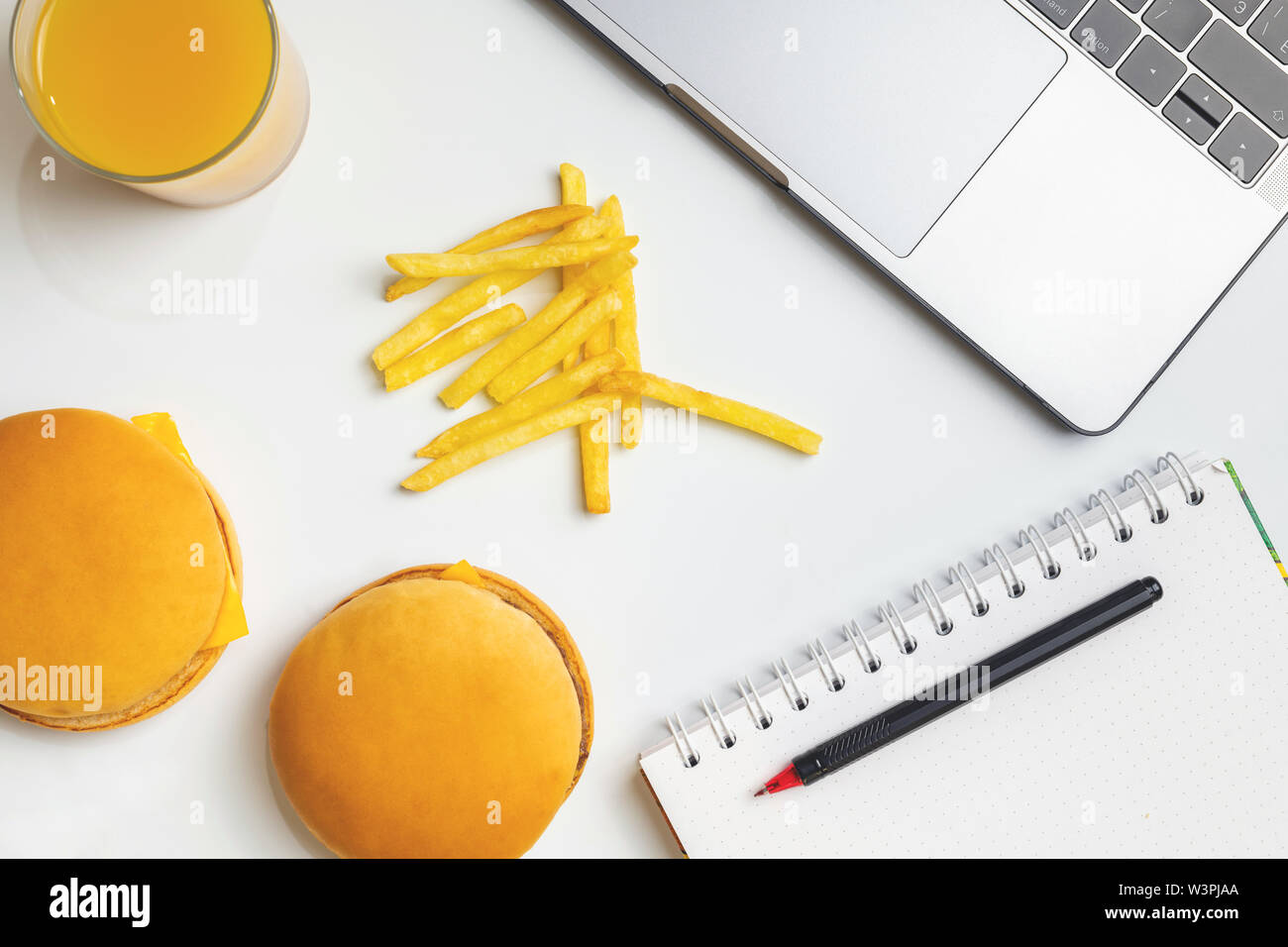 Fast food at work snacking. Laptop, hamburger and french fry at ...