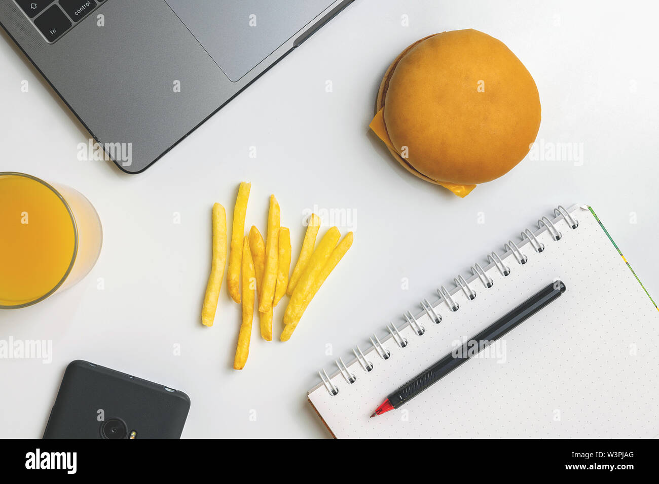 Fast food at work snacking. Laptop, phone, hamburger and french fry at ...