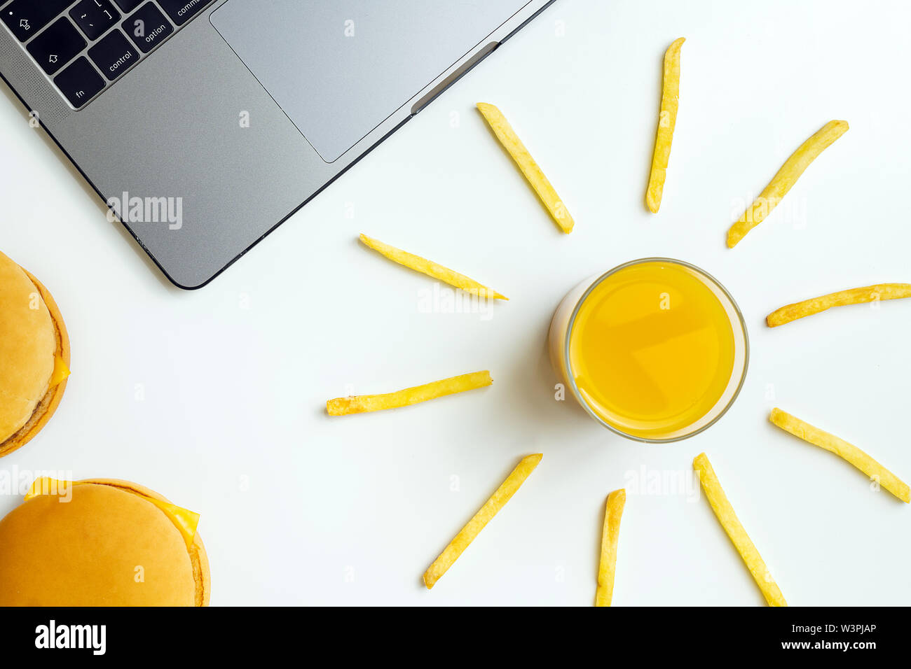 Fast food at work snacking. Laptop, hamburger and french fry at ...