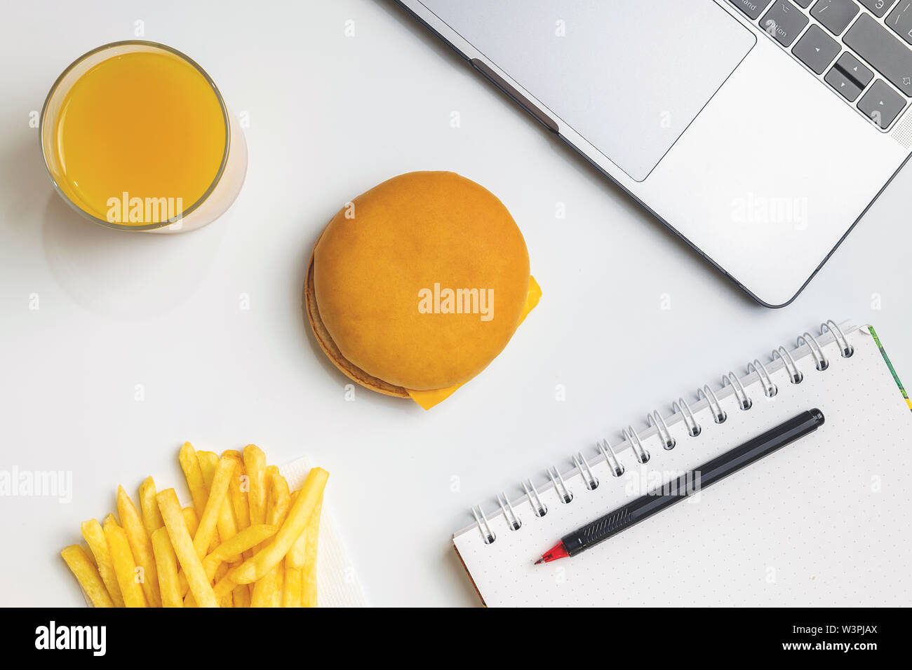 Fast food at work snacking. Laptop, hamburger and french fry at ...