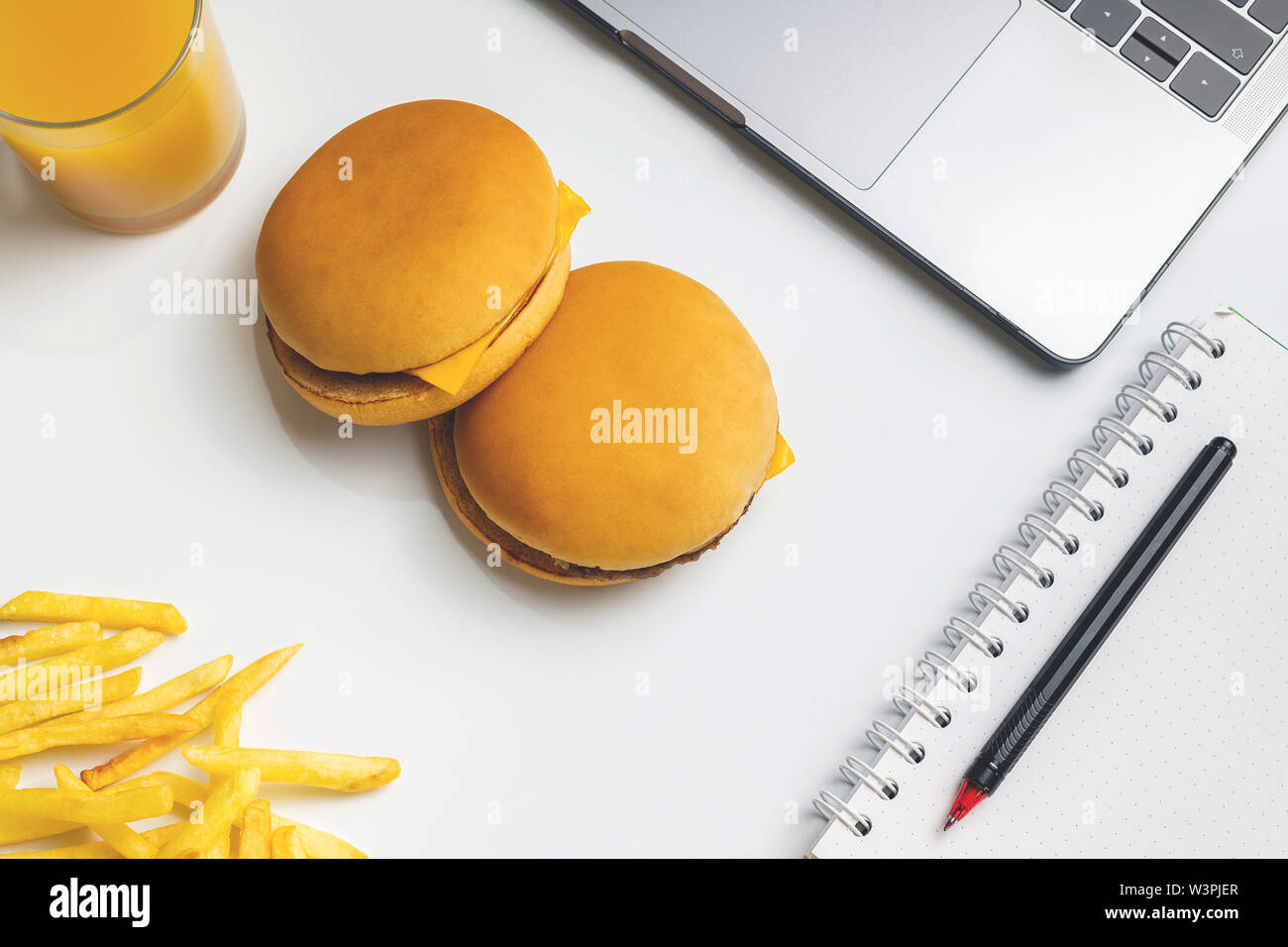 Fast food at work snacking. Laptop, two hamburgers and french fry at ...