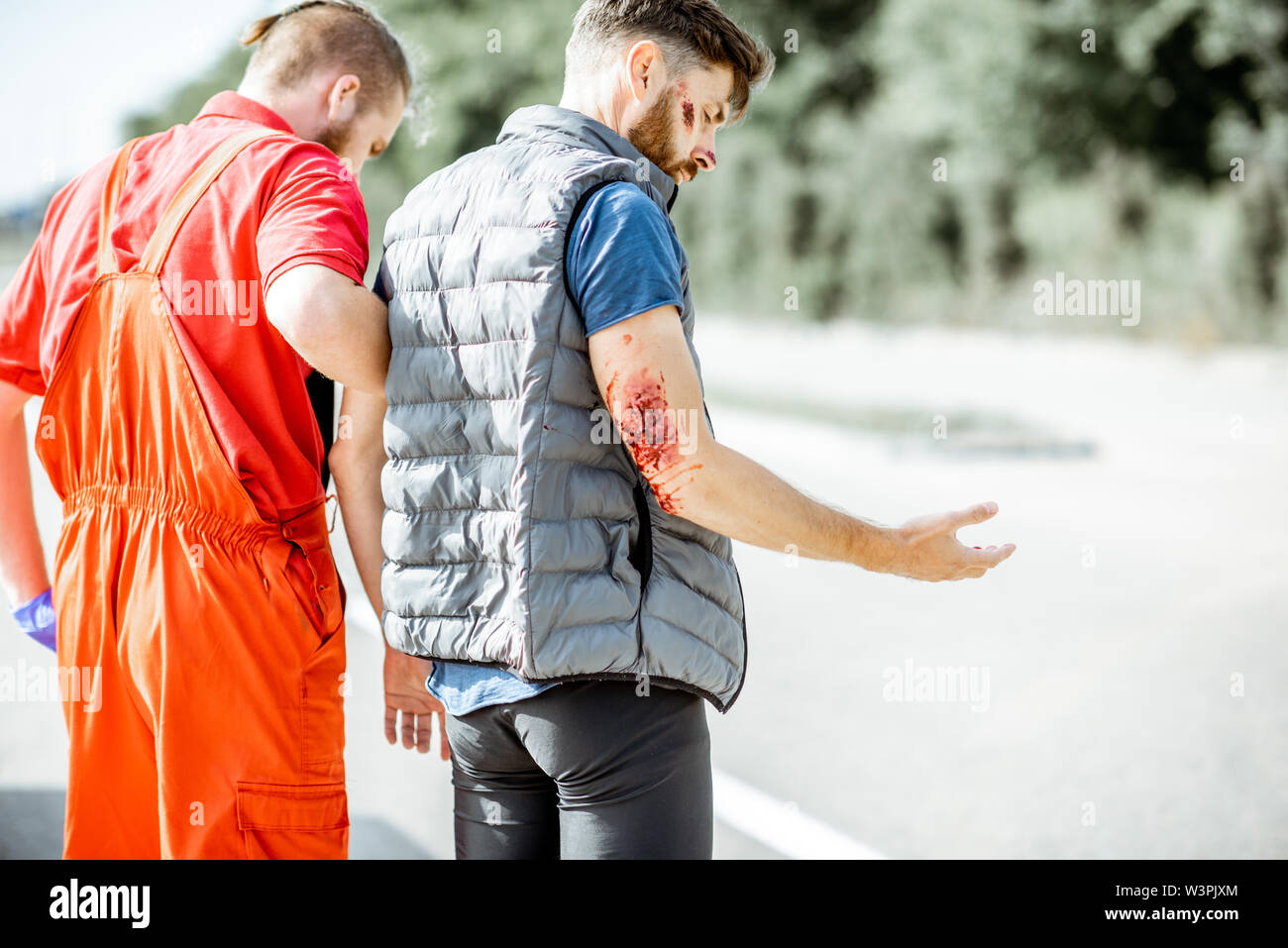 Medic in uniform helping injured man to walk, applying first aid after ...