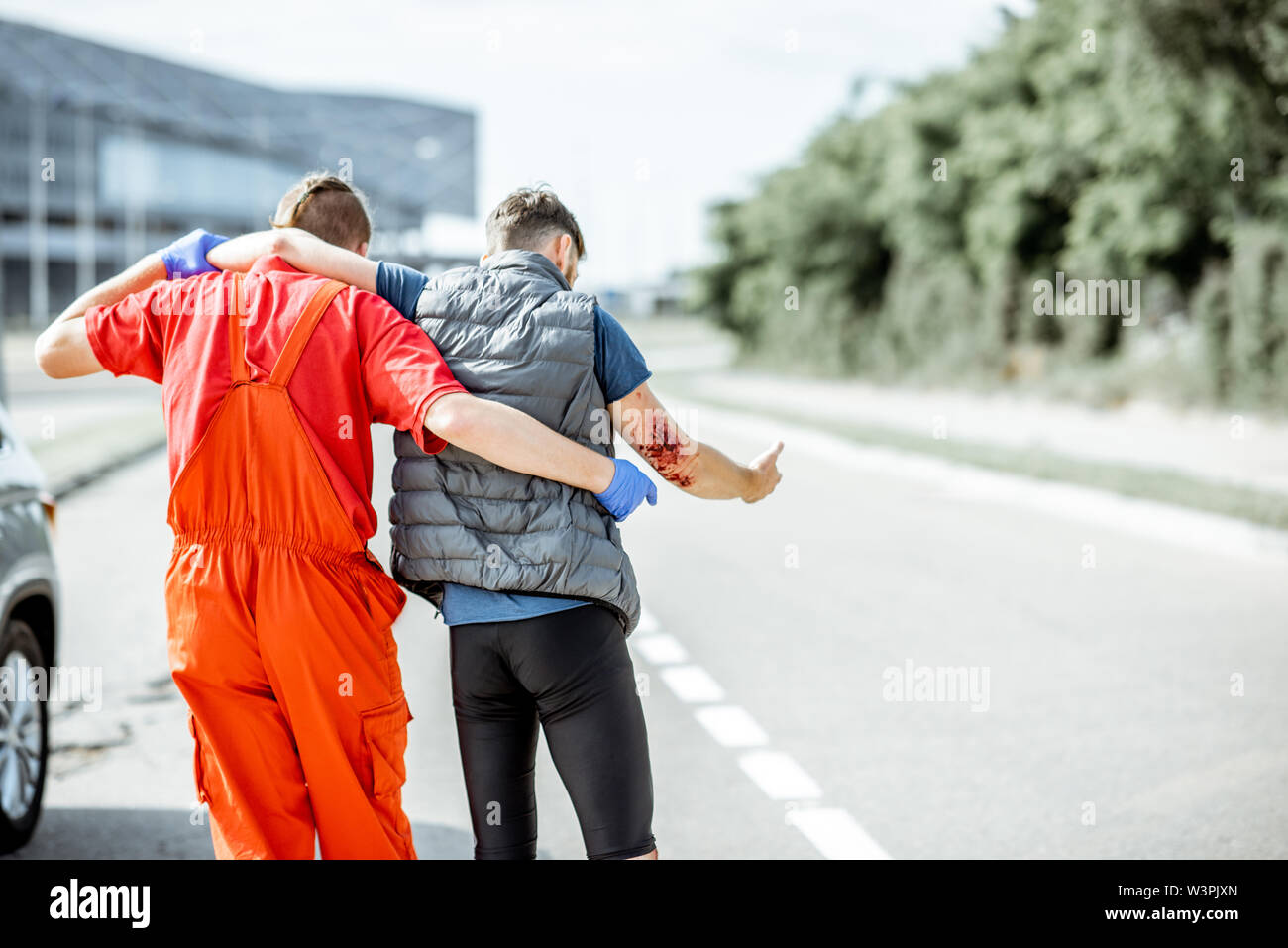 Medic in uniform helping injured man to walk, applying first aid after ...