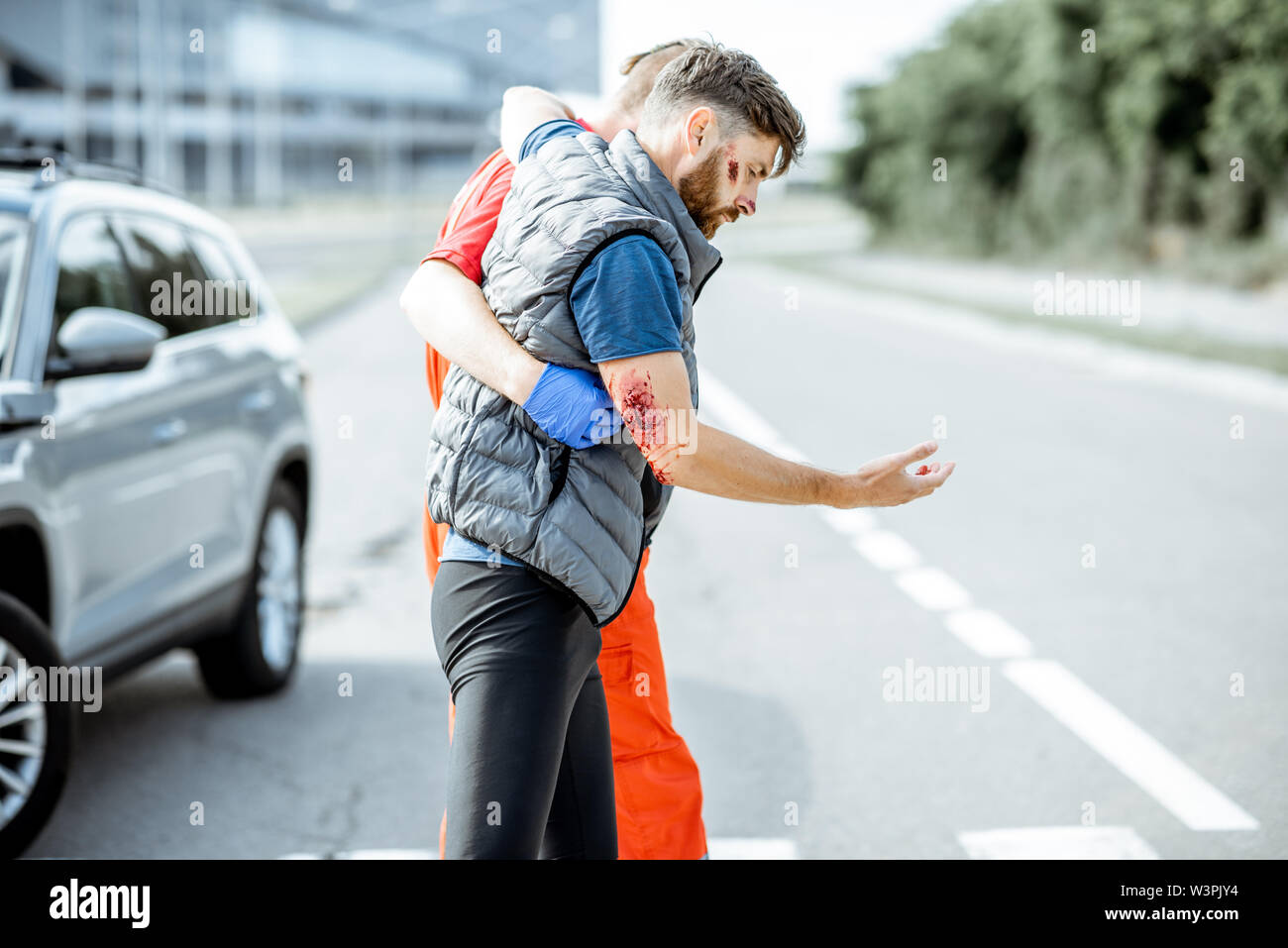 Medic in uniform helping injured man to walk, applying first aid after ...