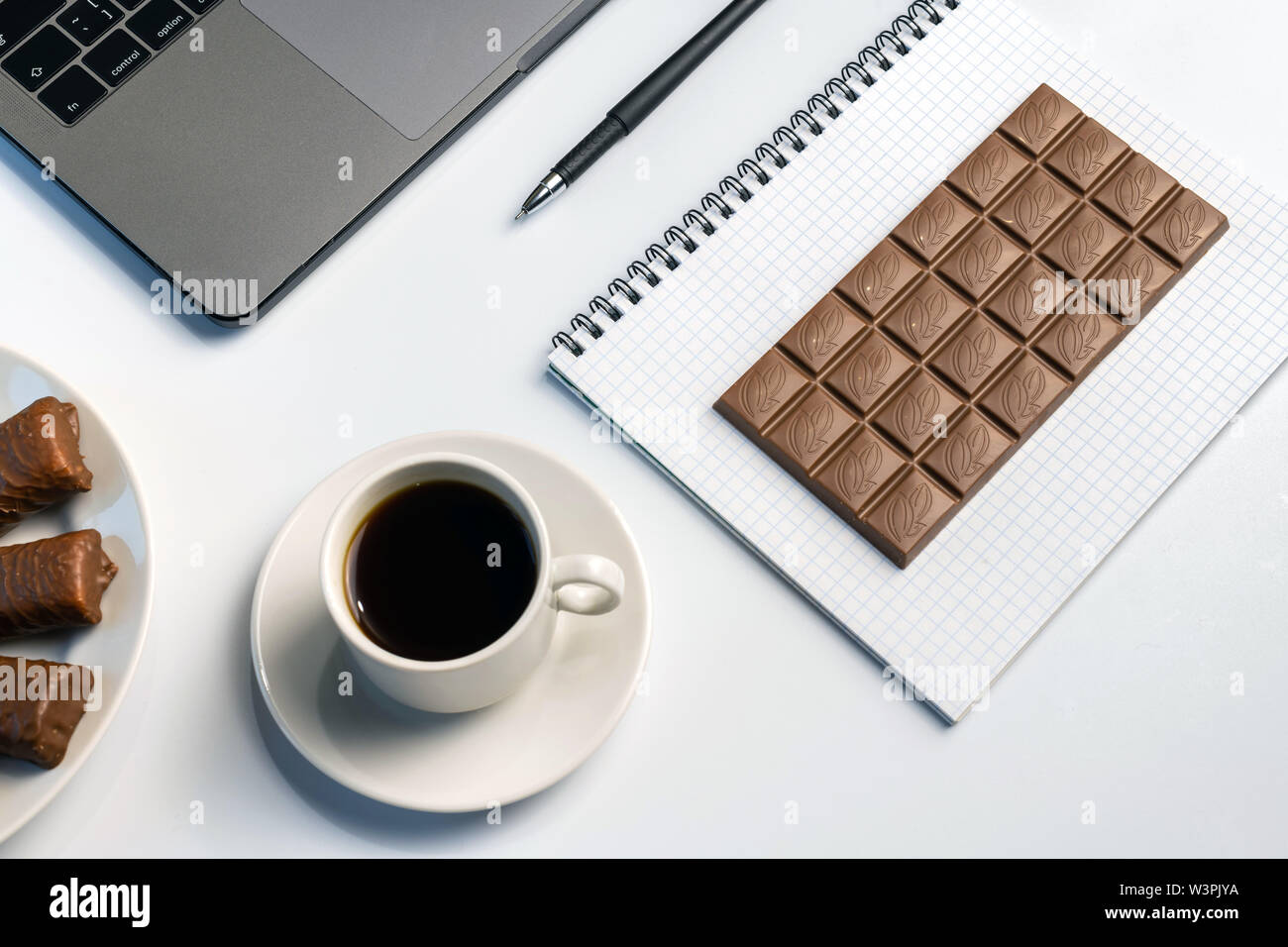 Snacking at work, have a bite concept. Laptop, candy and workbook with ...