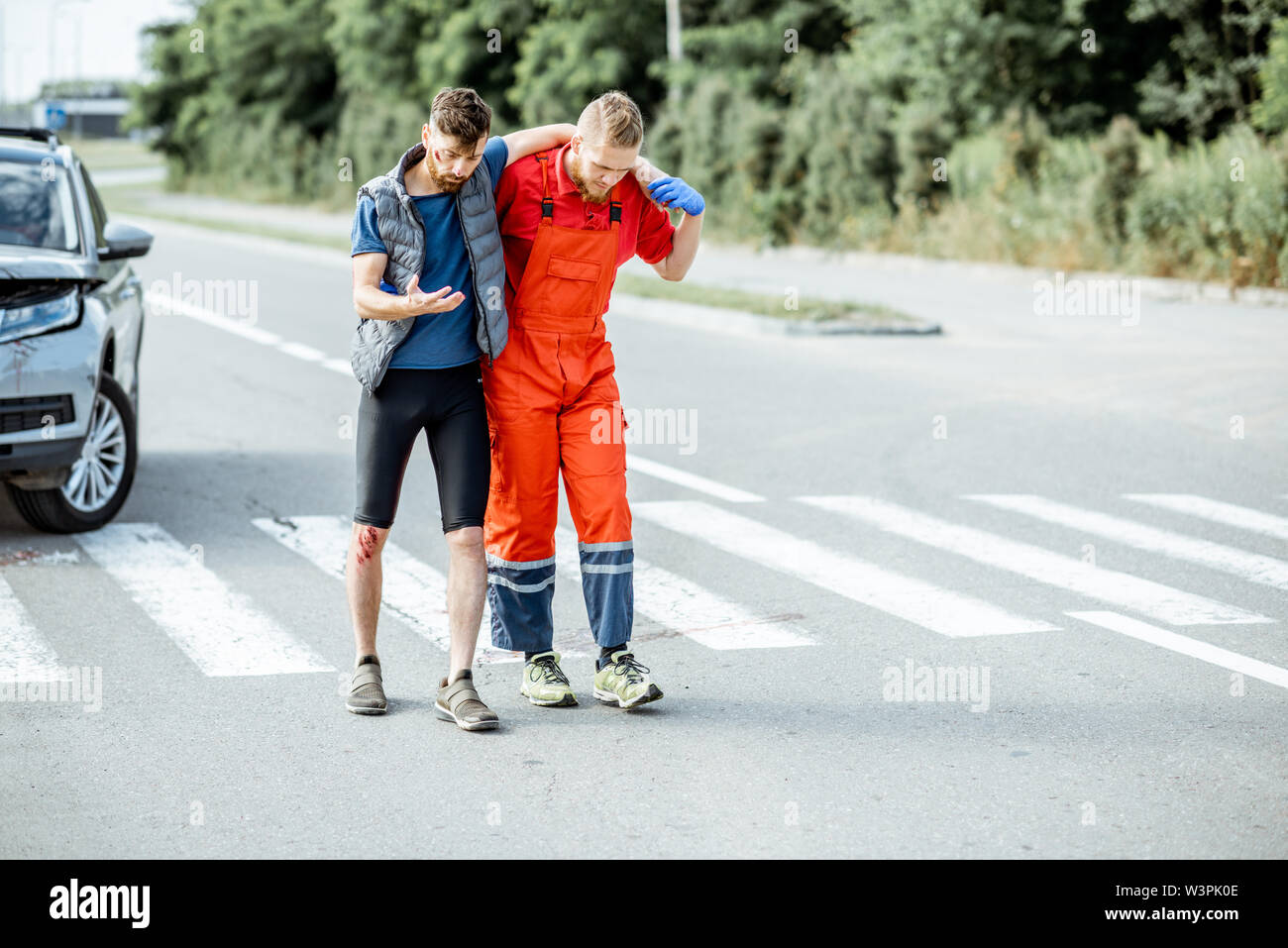 Medic in uniform helping injured man to walk, applying first aid after ...