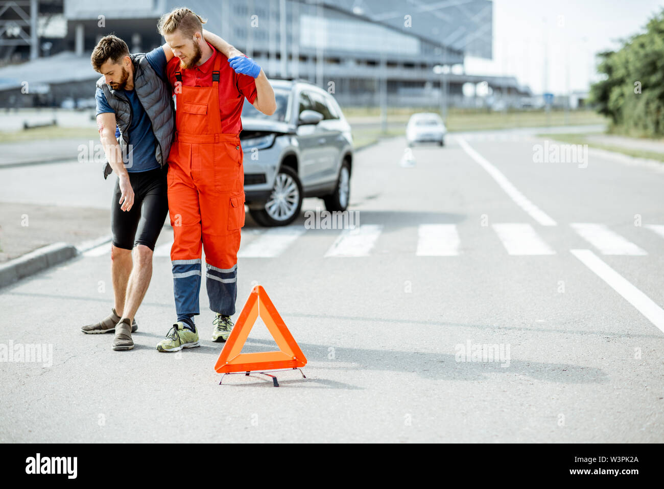 Medic in uniform helping injured man to walk, applying first aid after ...