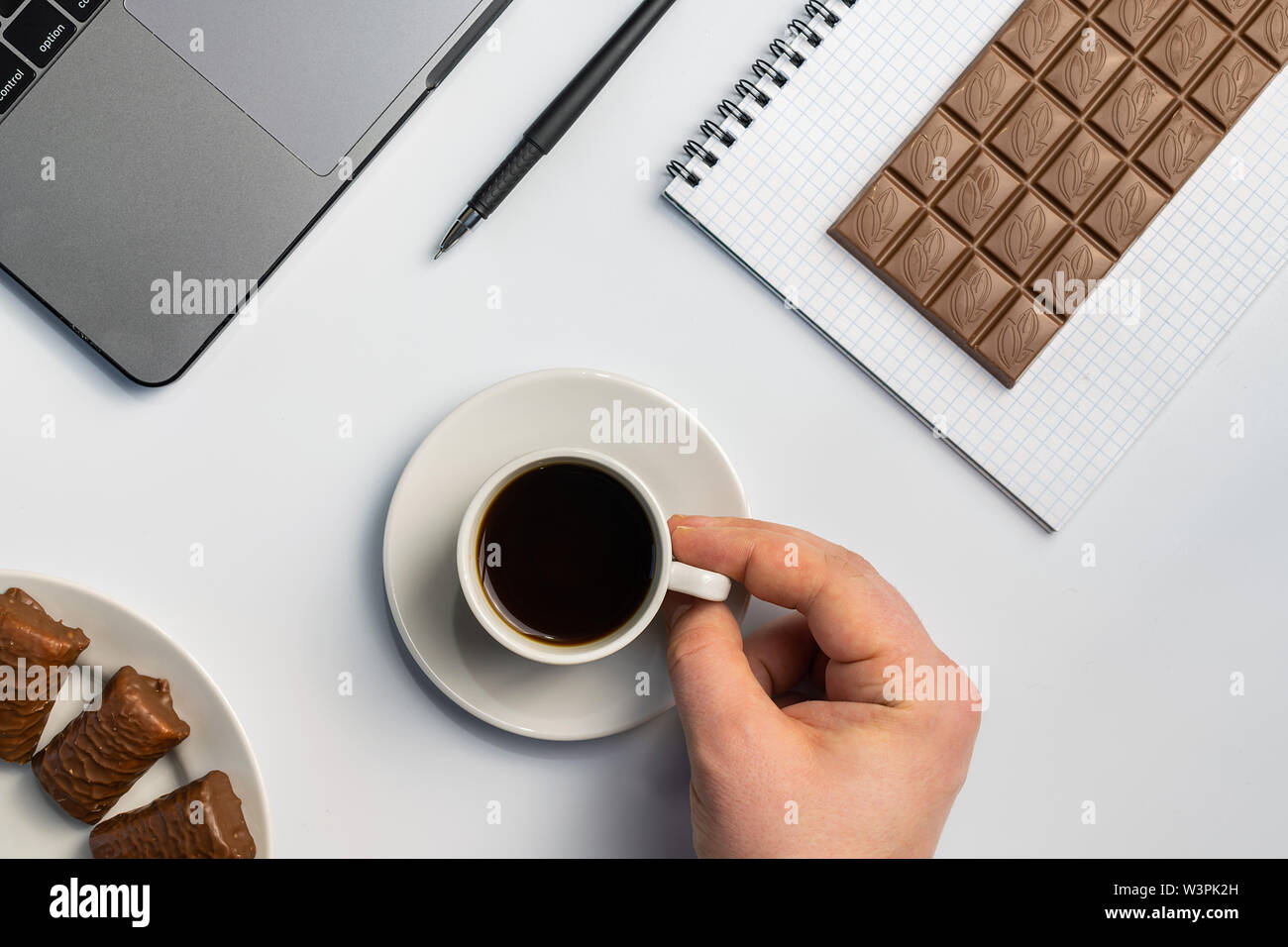 Snacking at work, have a bite concept. Laptop, candy and workbook with ...