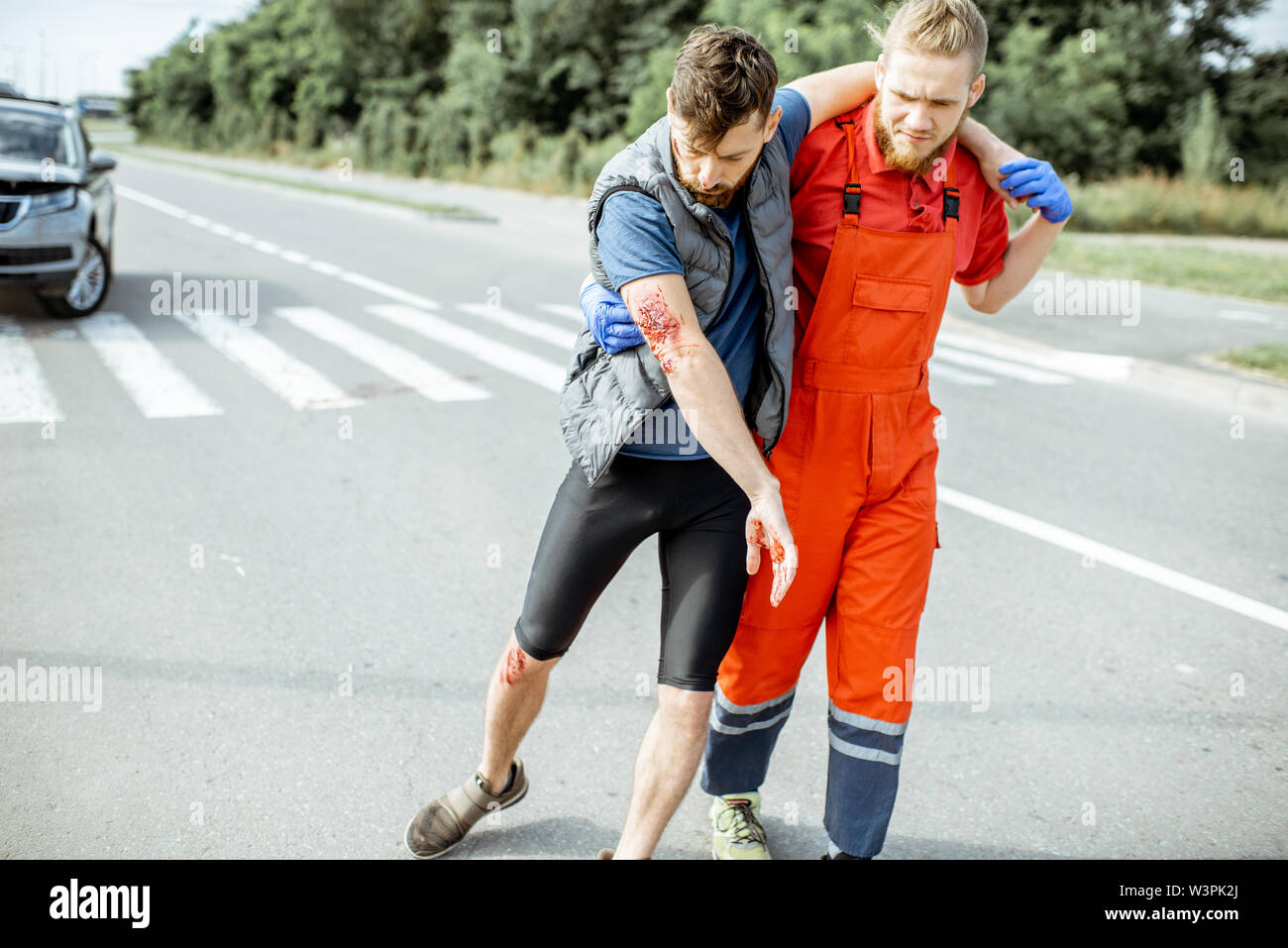 Medic in uniform helping injured man to walk, applying first aid after ...