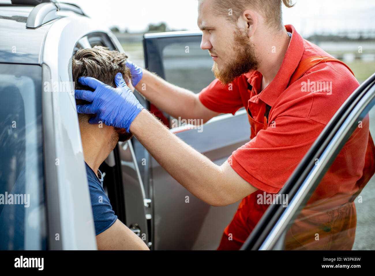 Ambulance worker examining facial injuries of a man sitting near the ...