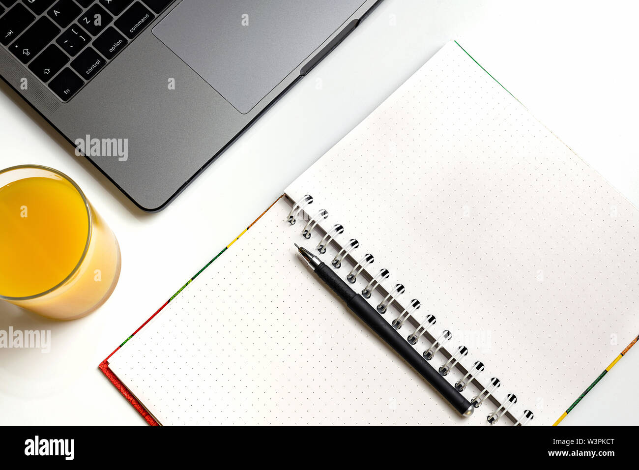 Orange juice on workplace. Laptop, glass of orange juice and notebook ...