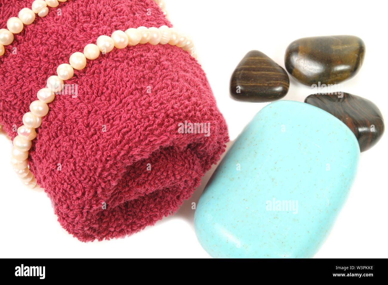 Towel with pearls, peeling soap and massage pebbles over white. Spa ...