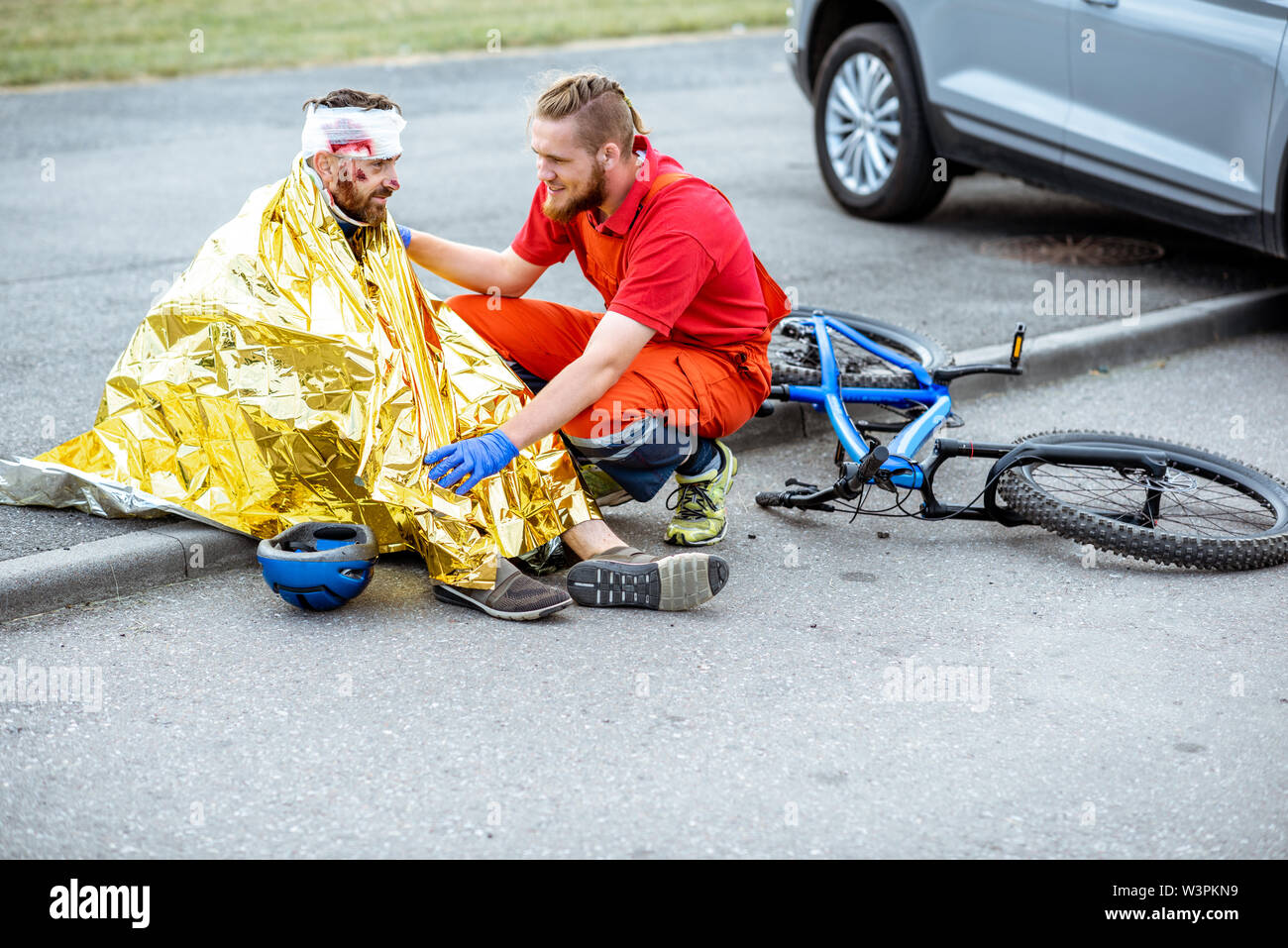 Ambluence worker covering injured man with thermal blanket, providing ...