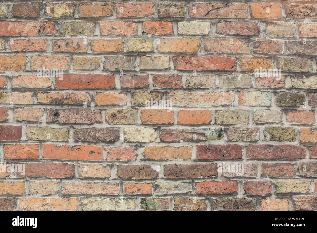 Wall made from red and sometimes colorful bricks of regular shapes and ...