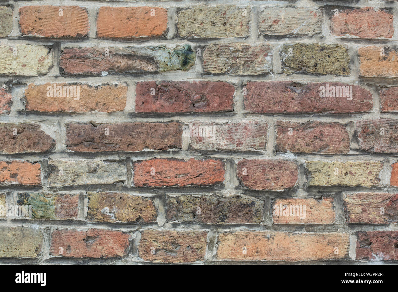 Wall made from red and sometimes colorful bricks of regular shapes and ...