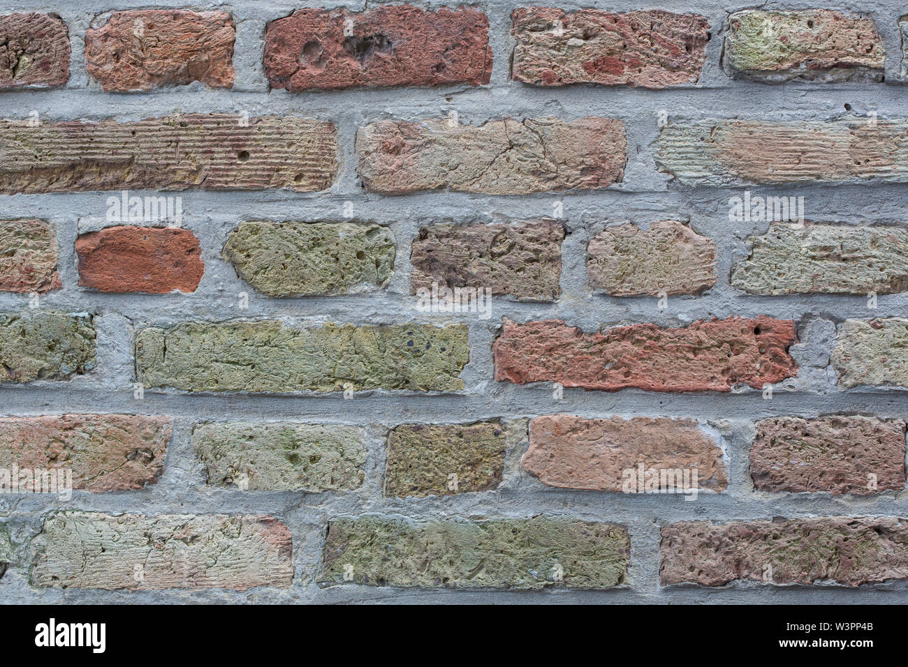 Wall made from red and sometimes colorful bricks of regular shapes and ...