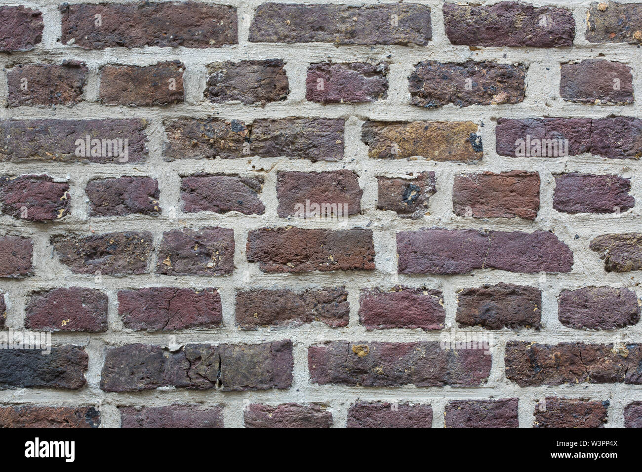 Wall made from red and sometimes colorful bricks of regular shapes and ...