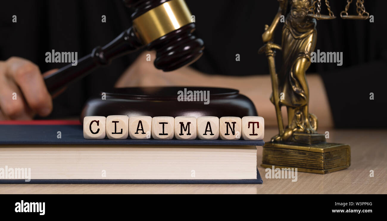 Word CLAIMANT composed of wooden dices. Wooden gavel and statue of ...