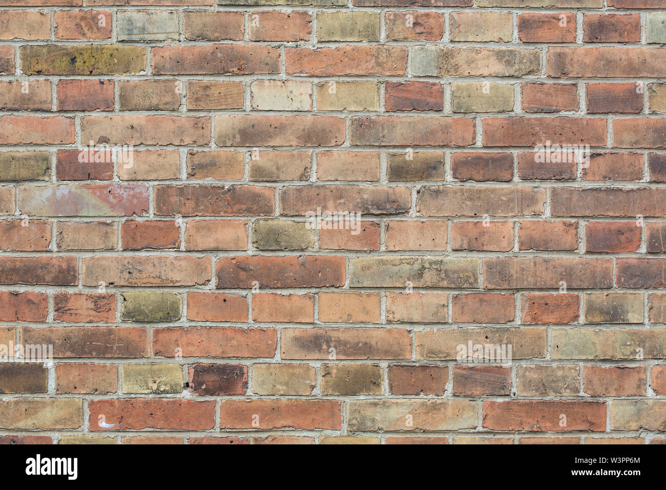 Wall made from red and sometimes colorful bricks of regular shapes and ...