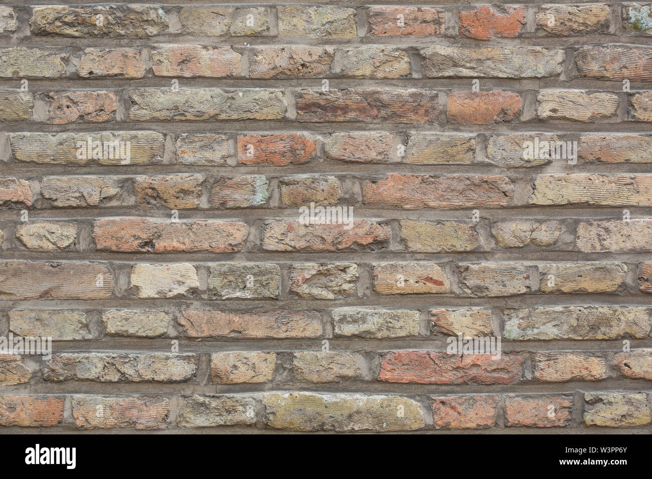 Wall made from red and sometimes colorful bricks of regular shapes and ...