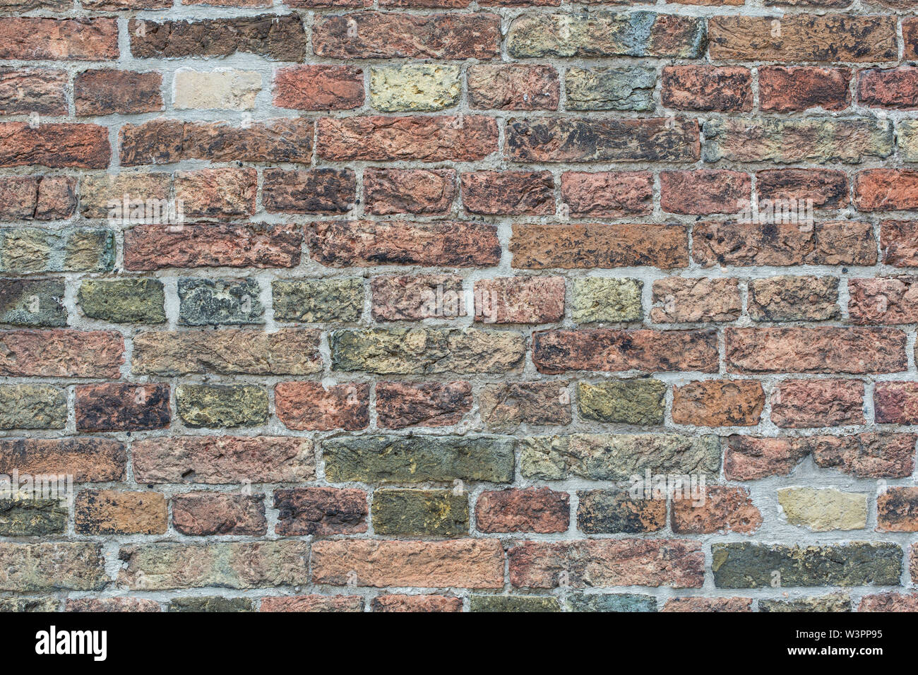 Wall made from red and sometimes colorful bricks of regular shapes and ...