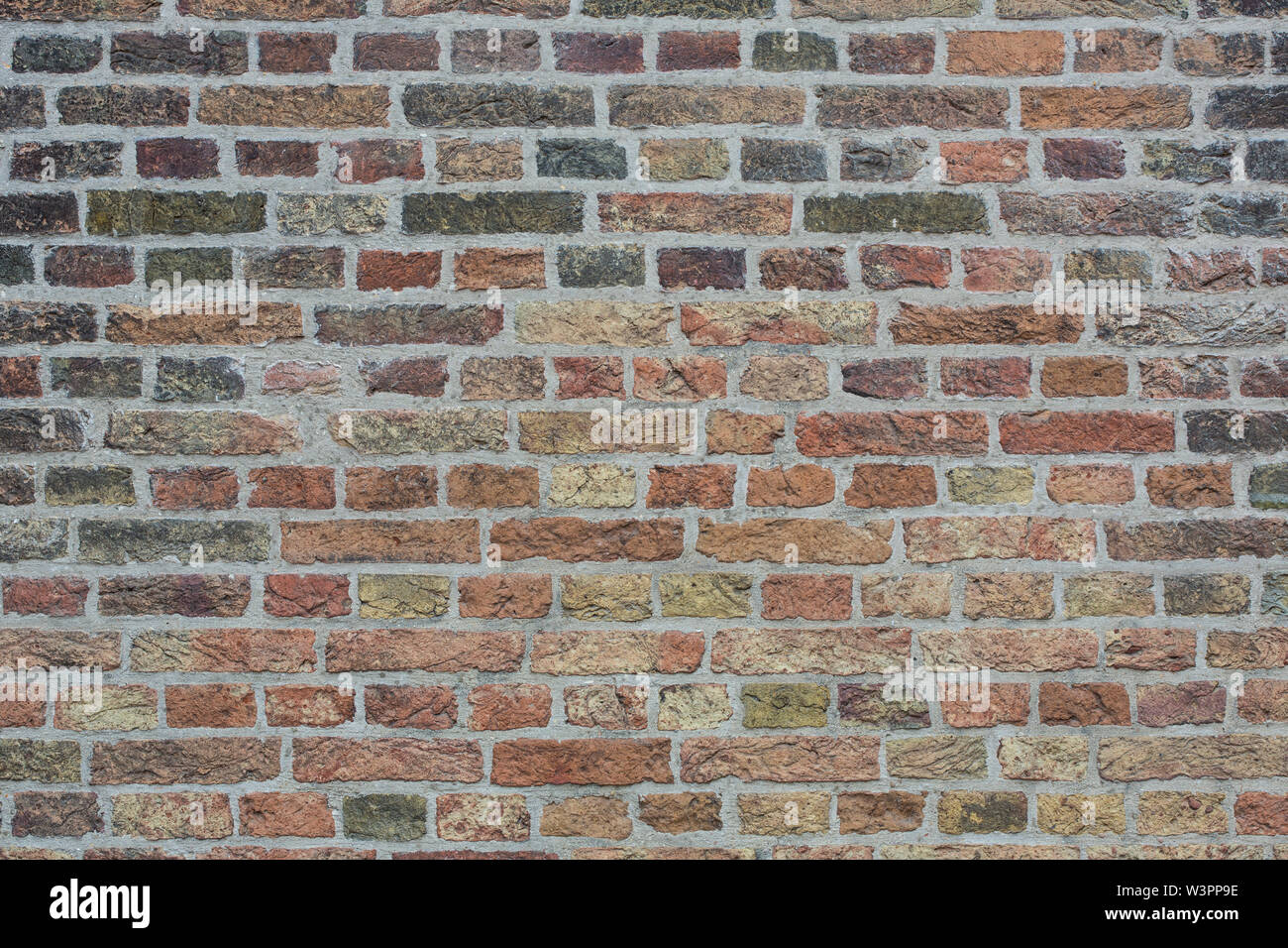 Wall made from red and sometimes colorful bricks of regular shapes and ...