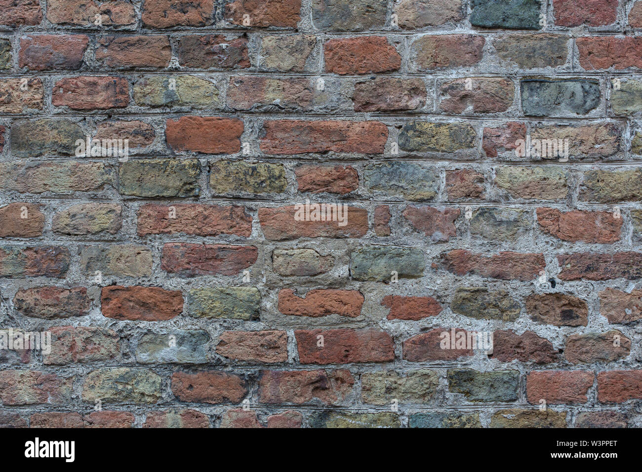 Wall made from red and sometimes colorful bricks of regular shapes and ...