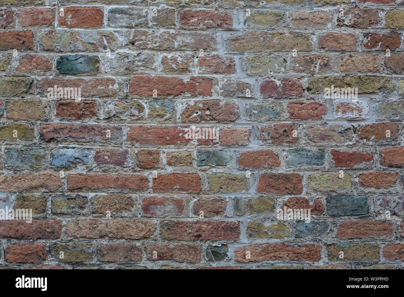 Wall made from red and sometimes colorful bricks of regular shapes and ...