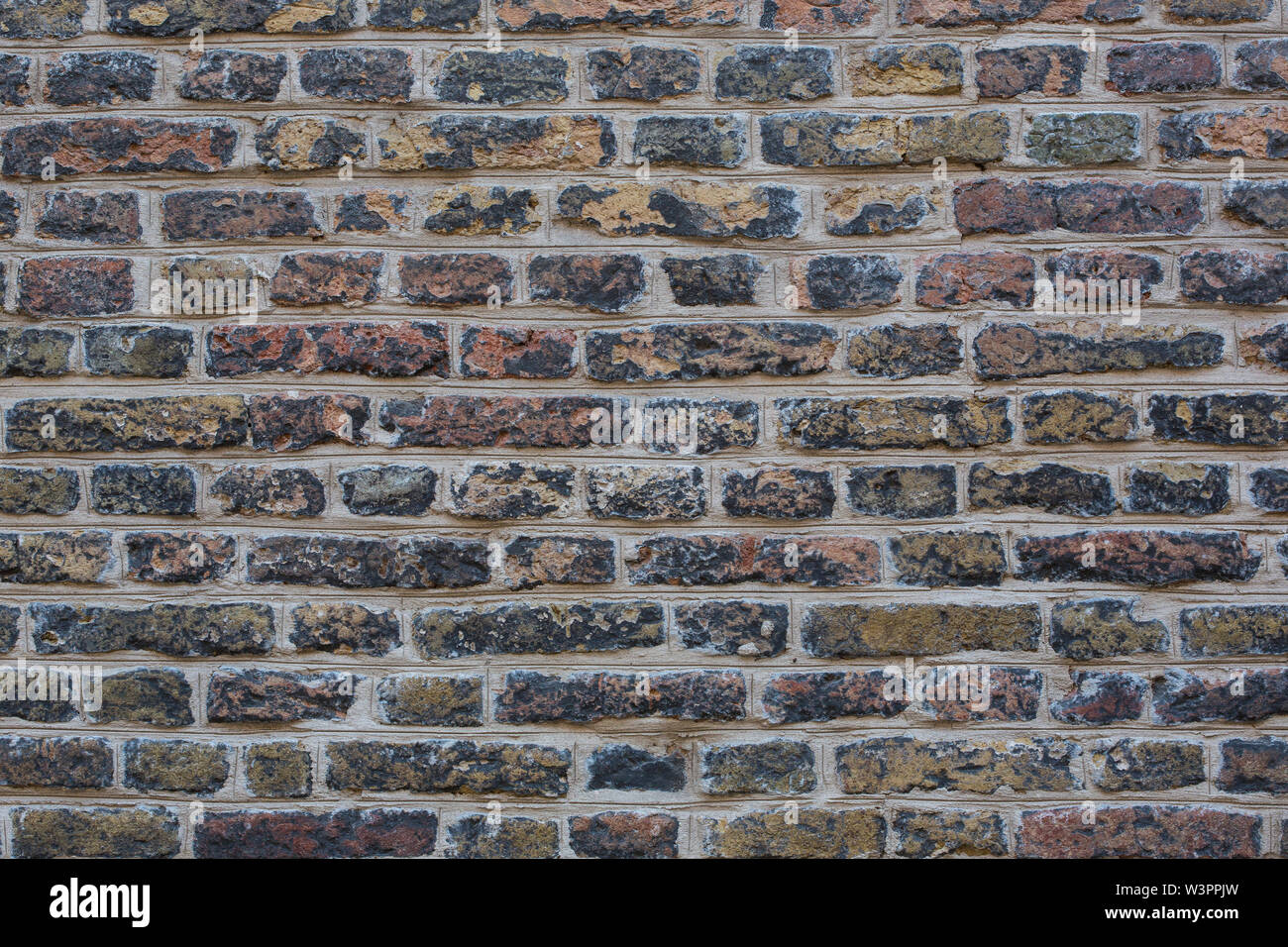 Wall made from red and sometimes colorful bricks of regular shapes and ...