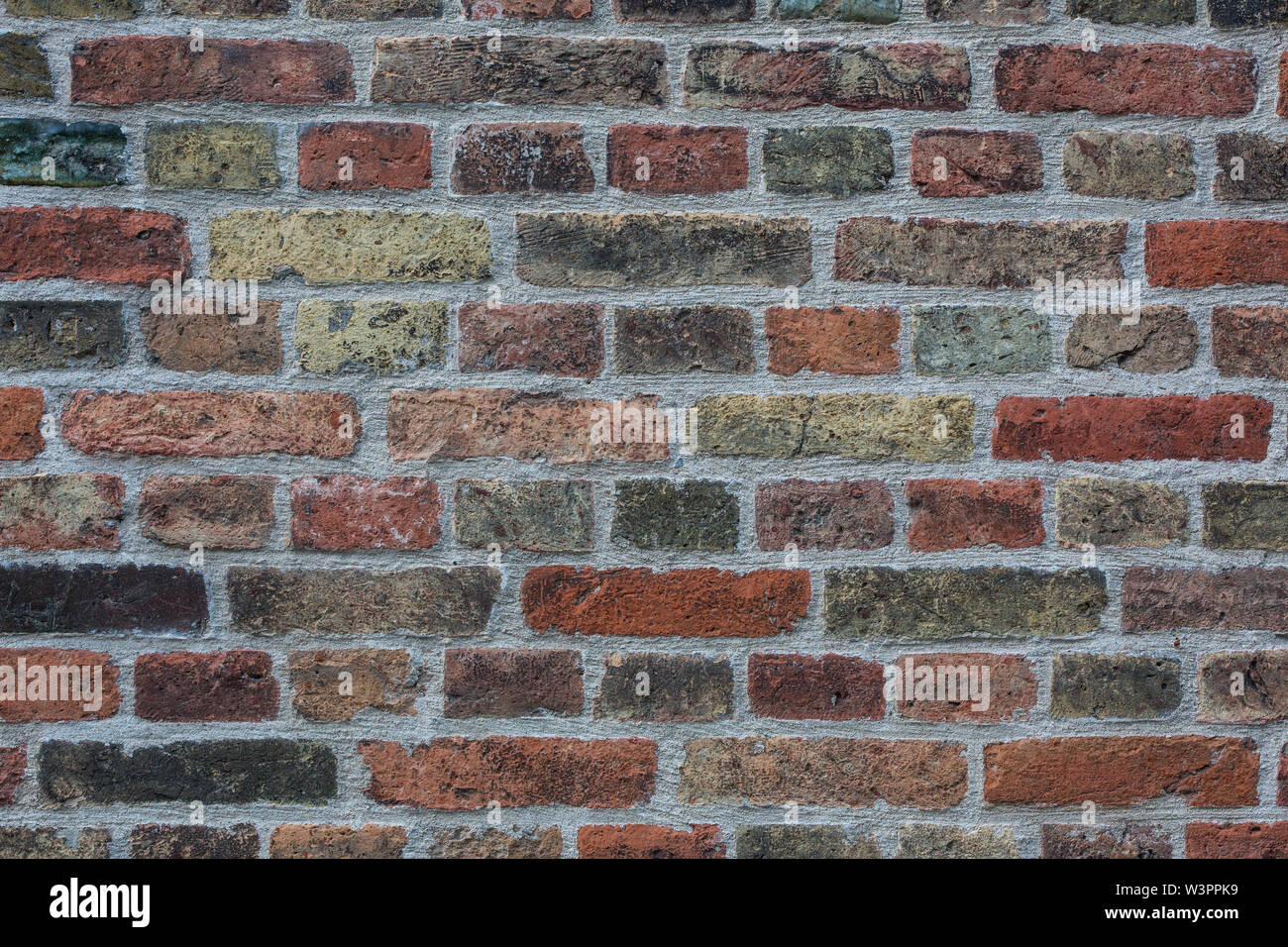 Wall made from red and sometimes colorful bricks of regular shapes and ...