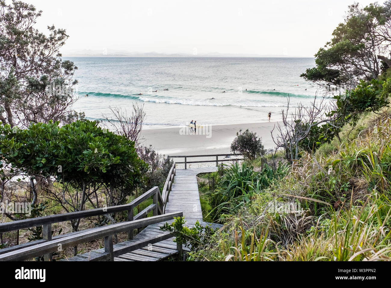Two surfers carrying their surfboards and walking along the shore at ...