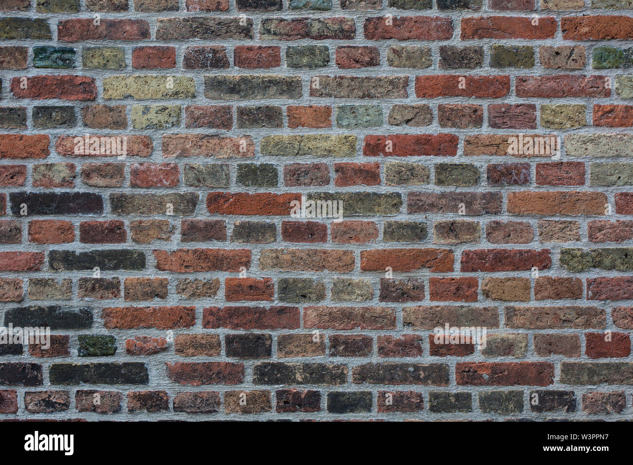 Wall made from red and sometimes colorful bricks of regular shapes and ...
