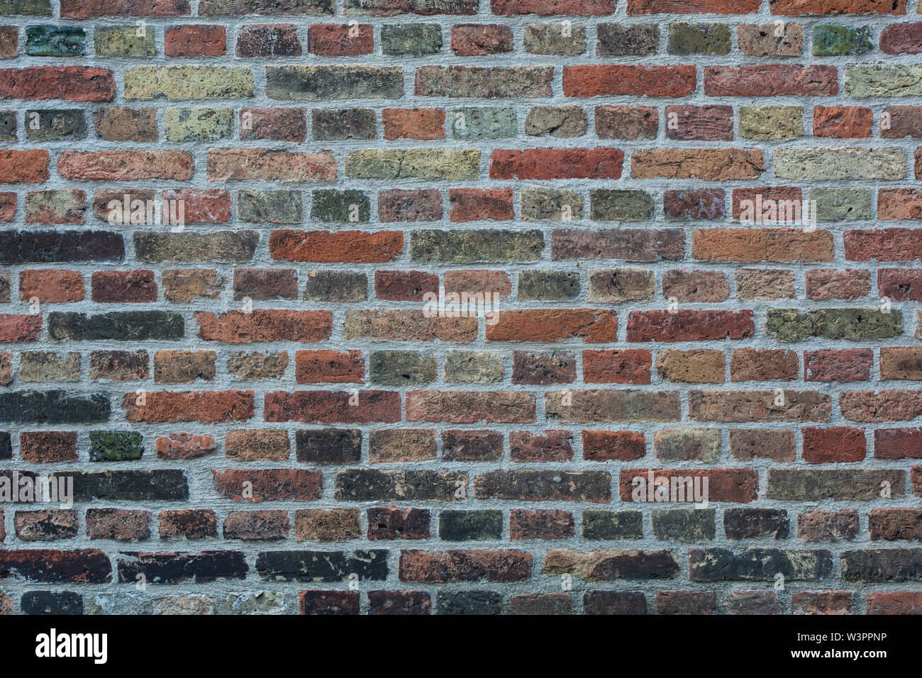 Wall made from red and sometimes colorful bricks of regular shapes and ...