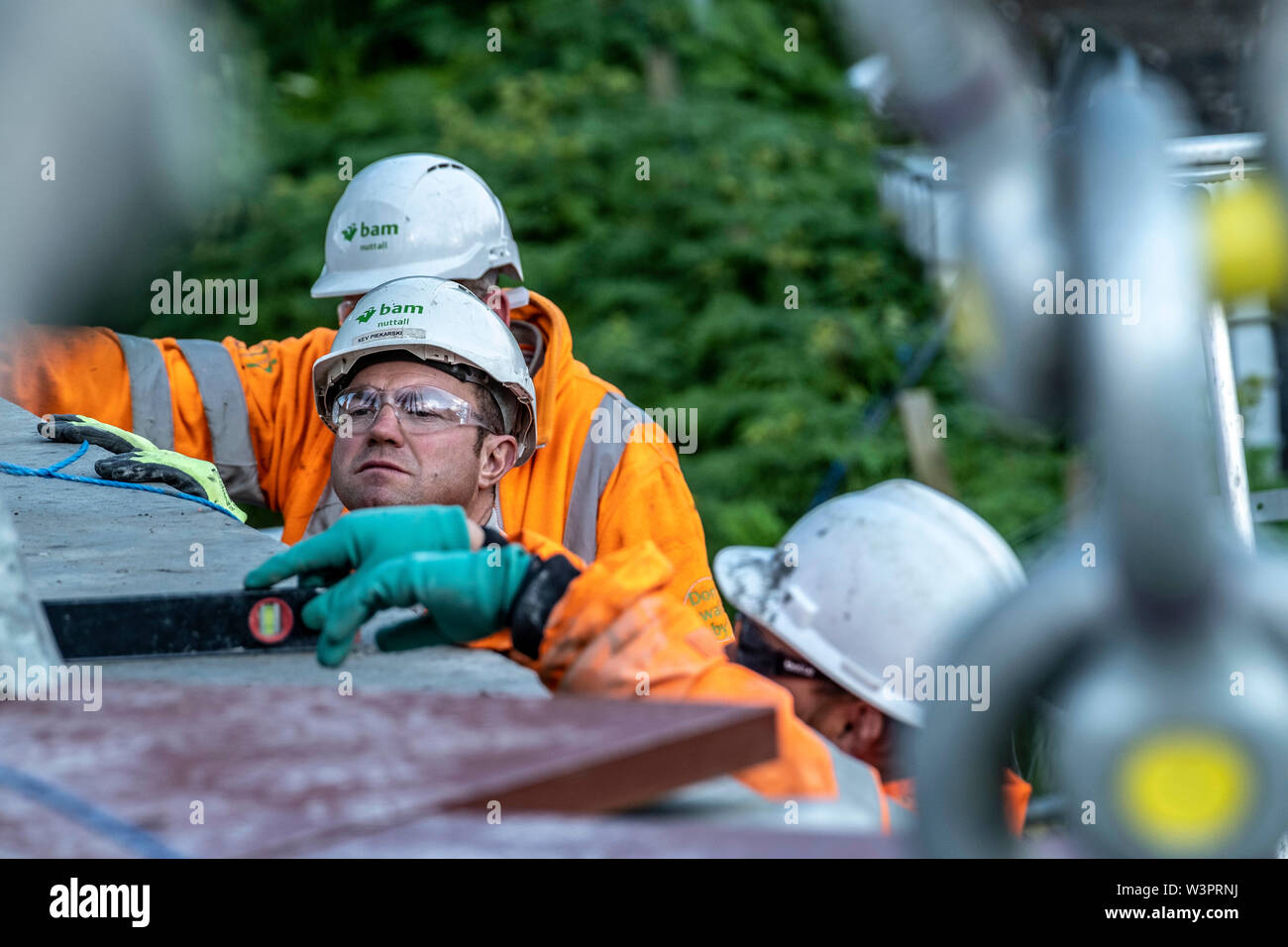 Railway workers constructing railway and lifting rail bridge into place ...