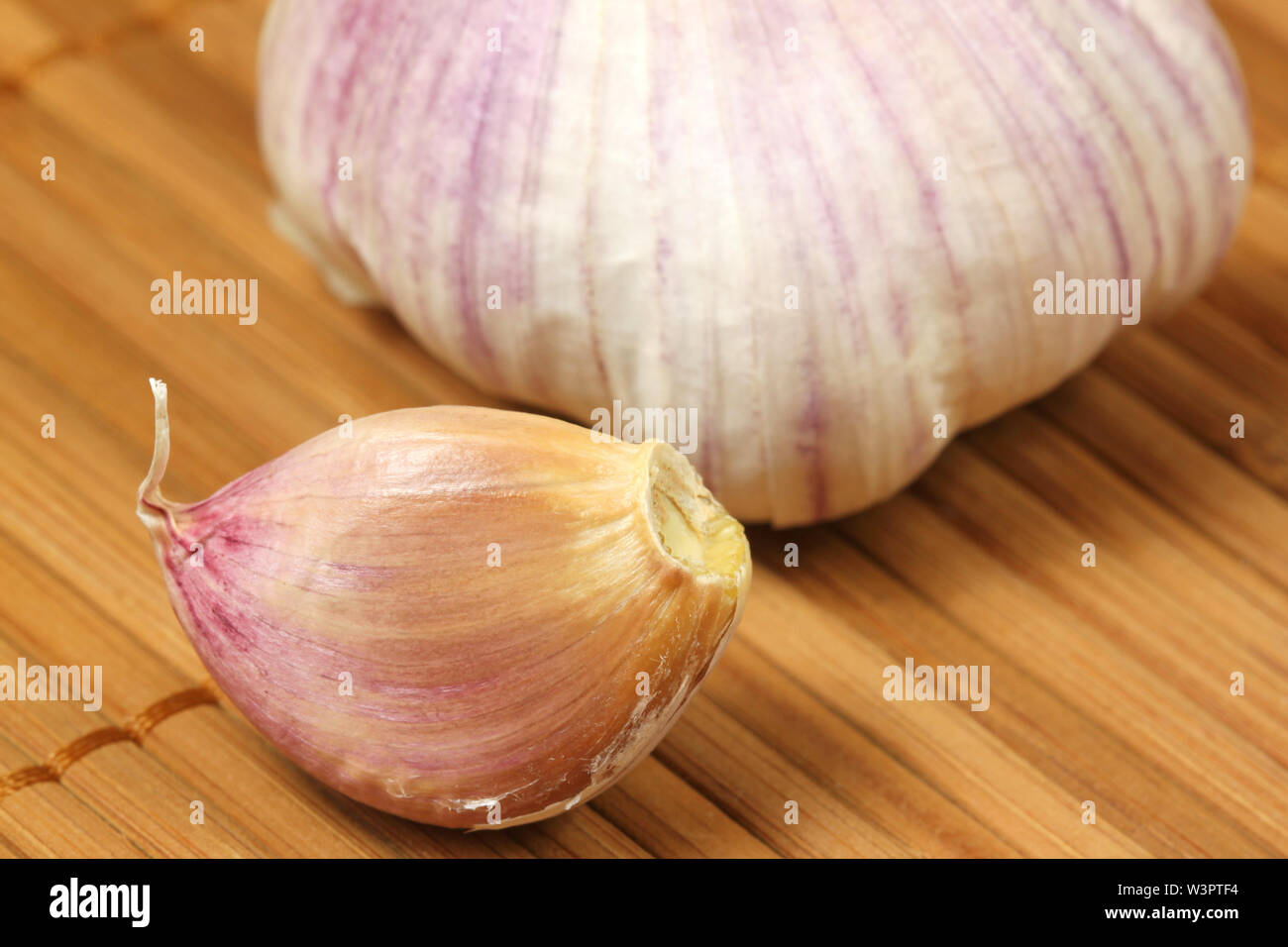 Garlic clove and head closeup on bamboo background Stock Photo - Alamy