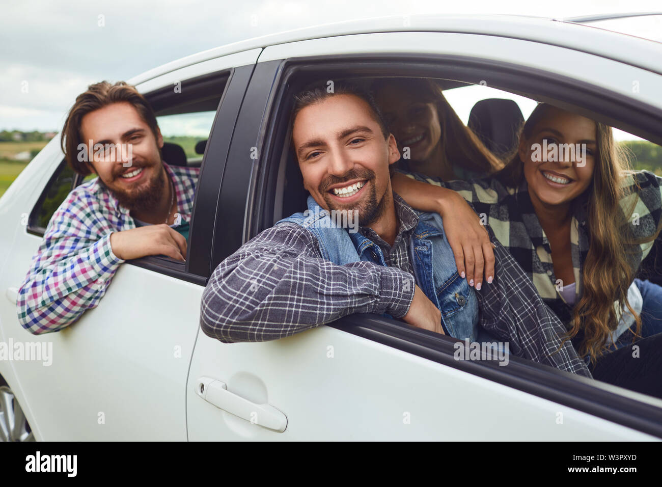 A group of happy friends travelers are driving in a car on road Stock ...
